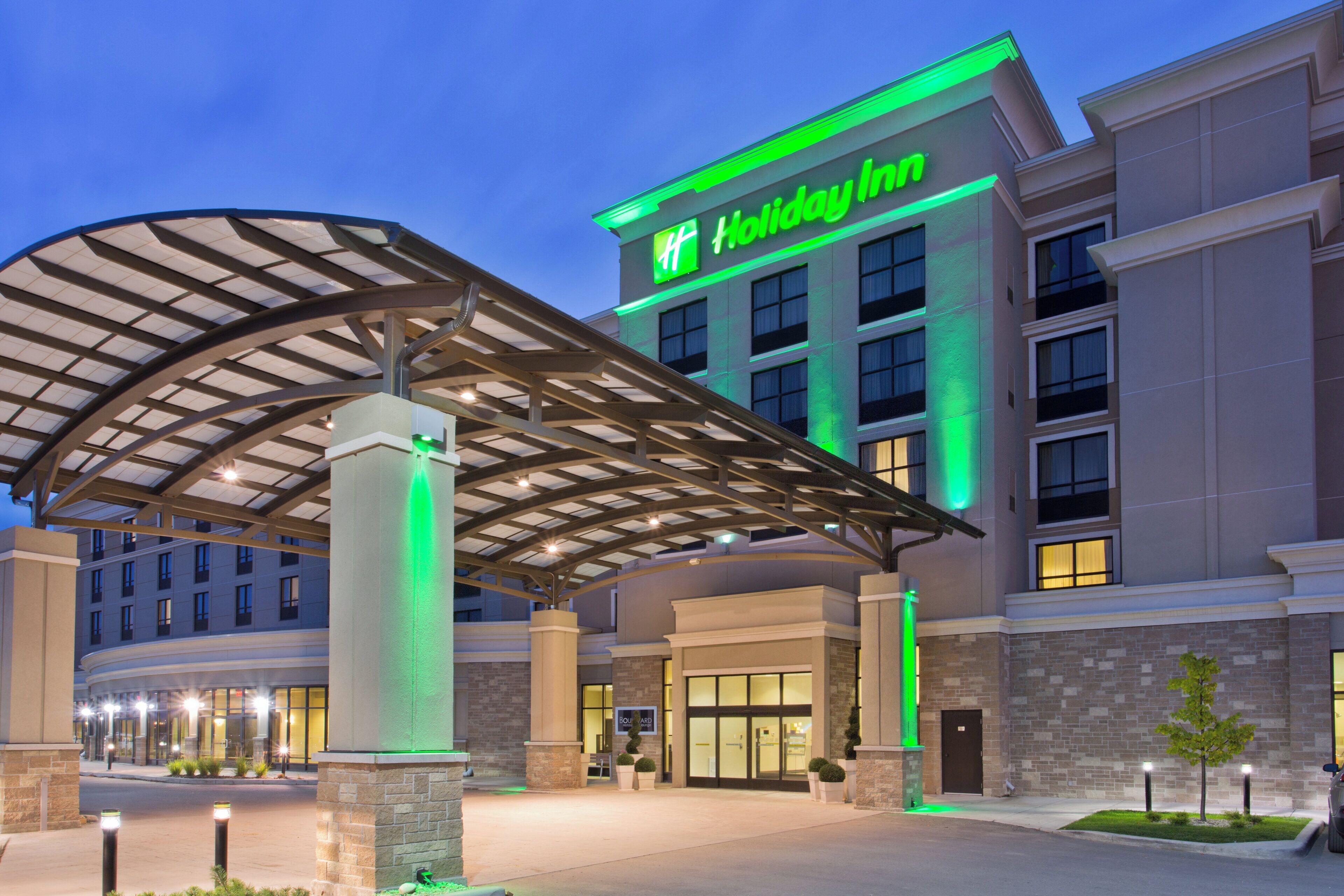 Um hotel Holiday Inn com entrada coberta e fachada de tijolos.