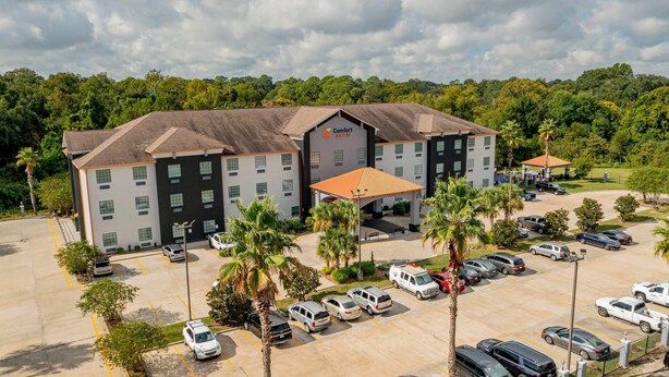 Um hotel Comfort Suites com estacionamento, vários edifícios e áreas verdes ao redor.