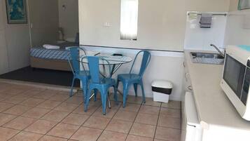 Uma cozinha compacta com micro-ondas, pia e pequena área de refeições com cadeiras azuis.