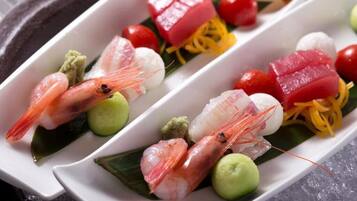 Variedade de sushi e sashimi sobre um prato retangular branco com gelo.