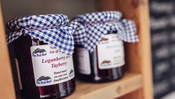 Potes de geleia de loganberry e tayberry sobre uma prateleira de madeira.