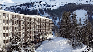 Um hotel com vários andares e design arquitetônico moderno, com varandas e vista para uma pista de esqui.