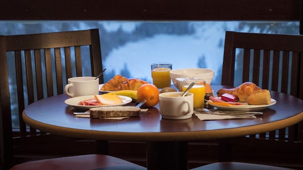 Mesa com itens de café da manhã e vista para a montanha.