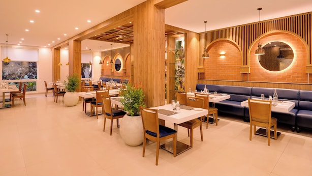 Um restaurante moderno com vigas de madeira, mesas redondas e assentos azuis.