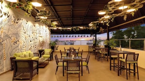 Um restaurante com teto alto, plantas penduradas e um mural na parede.