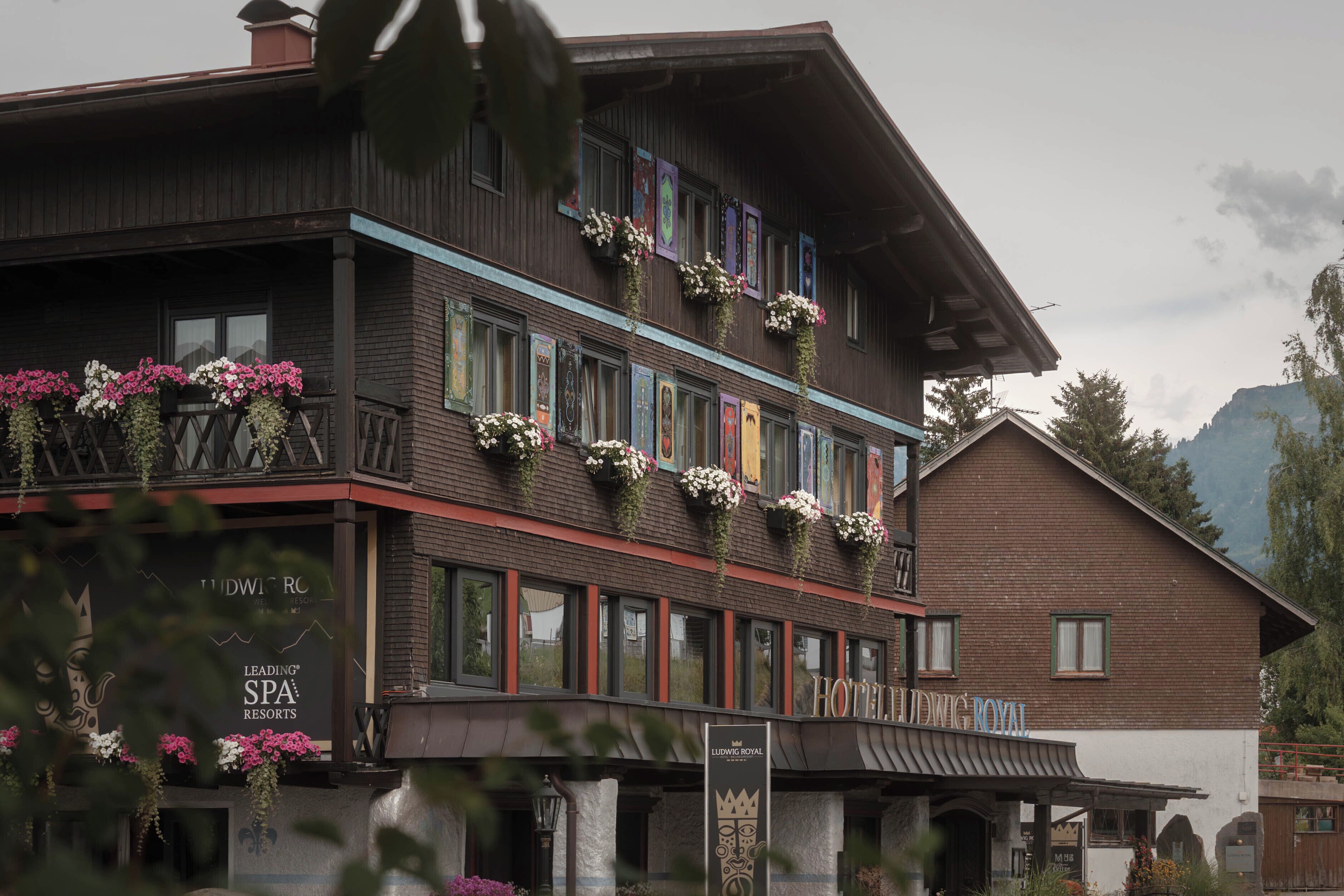 Um hotel com fachada de madeira tradicional, várias varandas com caixas de flores e uma placa indicando que é um resort spa de destaque.