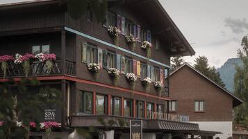 Um hotel com fachada de madeira tradicional, várias varandas com caixas de flores e uma placa indicando que é um resort spa de destaque.