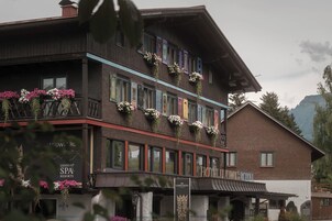 Um hotel com fachada de madeira tradicional, várias varandas com caixas de flores e uma placa indicando que é um resort spa de destaque.