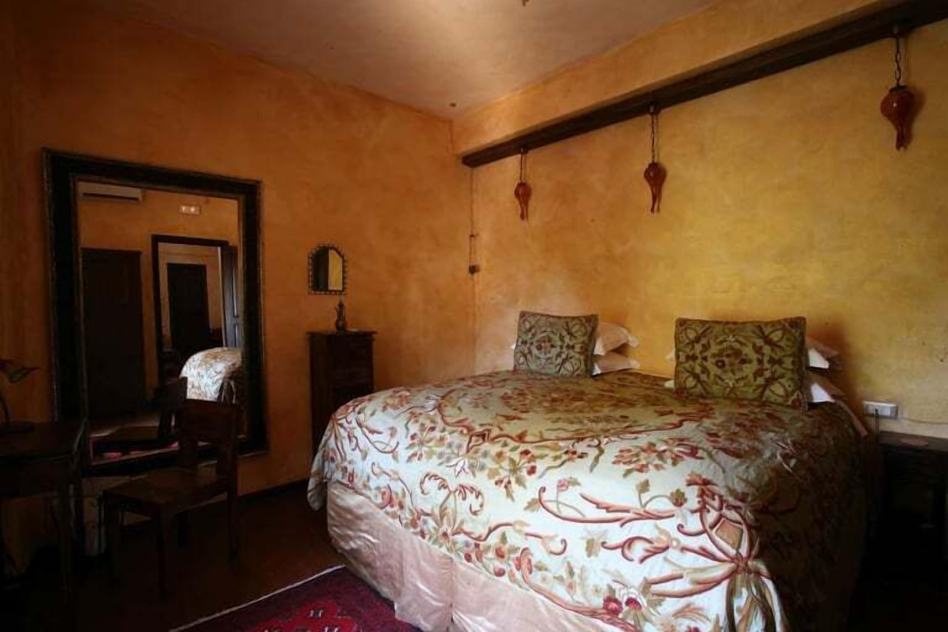 Quarto com uma cama grande, uma escrivaninha de madeira e um espelho.