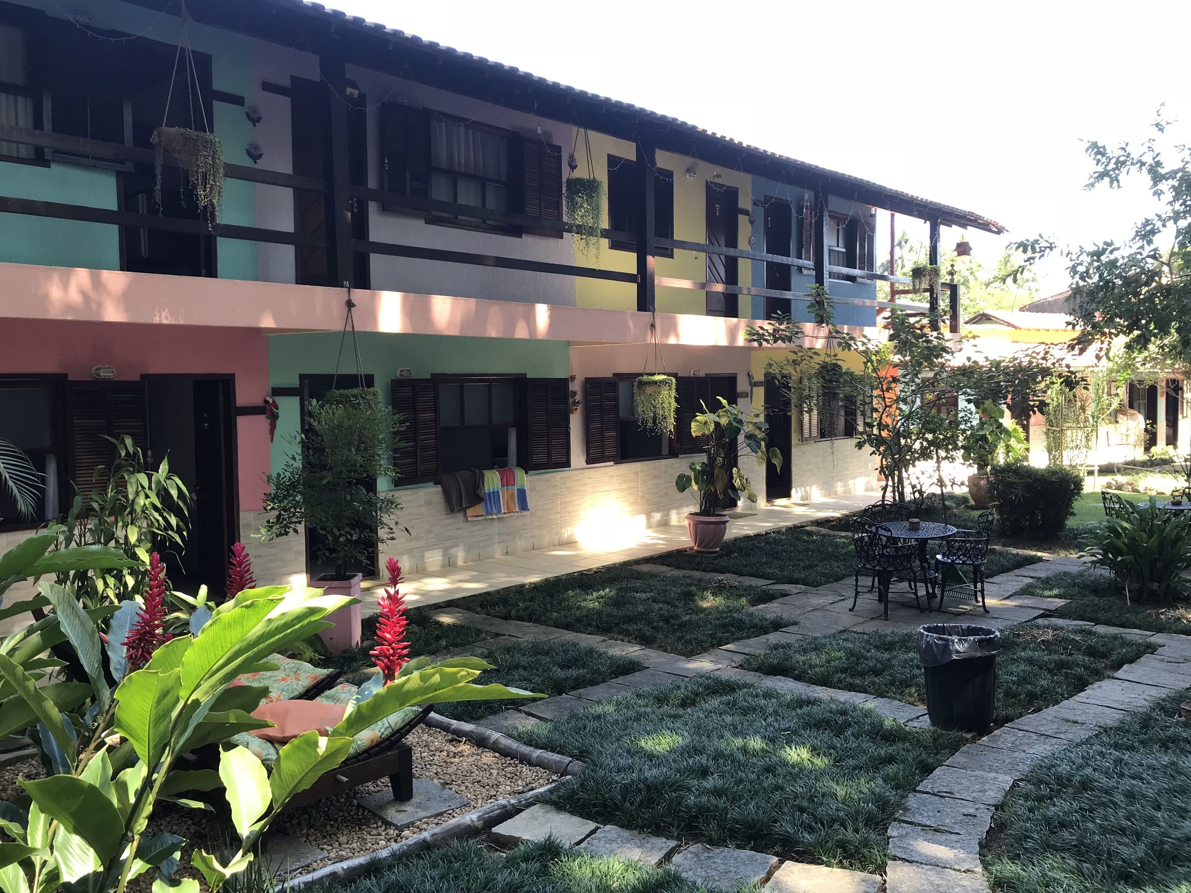 Um pátio com área de estar, plantas em vasos e um edifício com várias janelas e portas.
