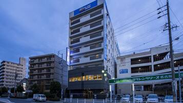 Um edifício de vários andares com a placa 'Darmy Inn', uma garagem de estacionamento e vários carros estacionados.