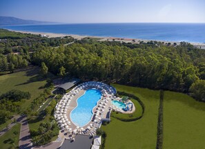 Vista aérea de um resort com uma piscina grande, áreas de estar e uma praia.