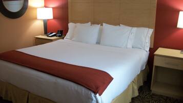 Quarto de hotel com cama grande, duas mesas de cabeceira, abajur e espelho na parede.