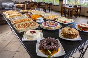 Uma mesa de buffet com diversos produtos de panificação e sobremesas.