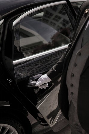 Um carro preto com a porta aberta, mostrando uma pessoa usando uma luva branca.