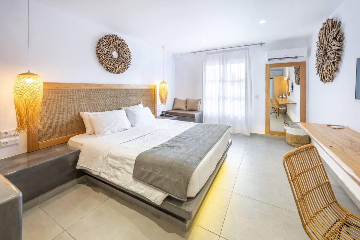 Quarto de hotel moderno com uma cama grande, mesas de cabeceira, uma escrivaninha e uma cadeira.