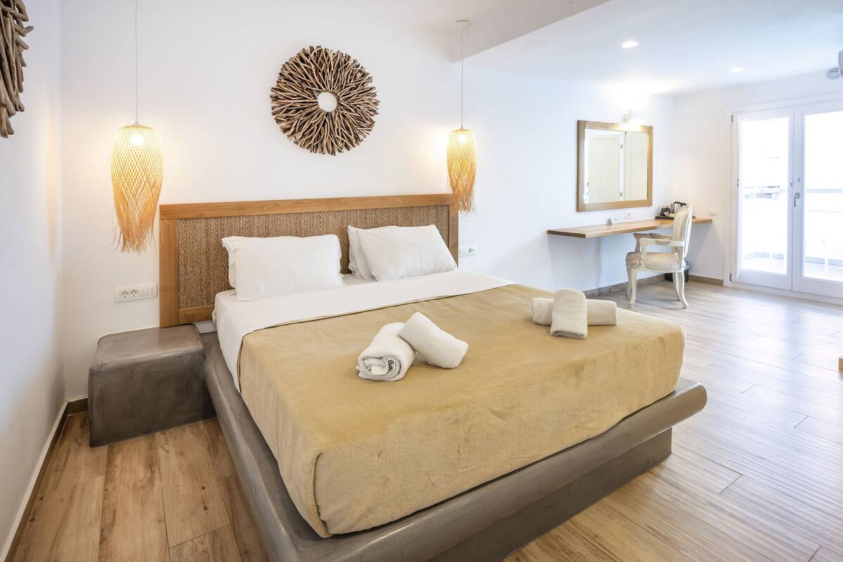 Quarto de hotel com uma cama grande, uma escrivaninha e uma cadeira.