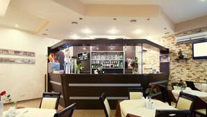 Um restaurante com área de bar, mesas e cadeiras, e uma parede de tijolos.