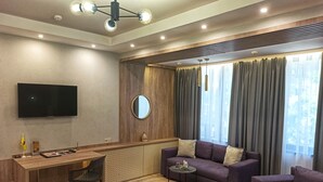 Uma sala de estar moderna com um sofá, uma mesa de centro, uma televisão e uma escrivaninha.