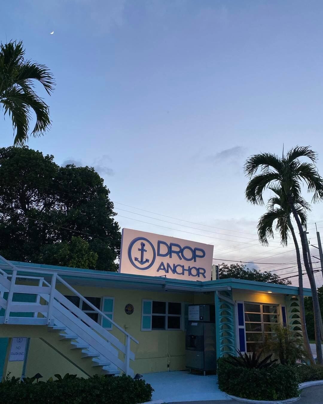 Um edifício com uma placa que diz "DROP ANCHOR" e uma escadaria que leva à entrada.