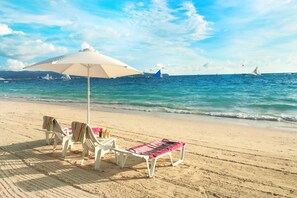 Na praia, praia de areia branca, espreguiçadeiras, guarda-sóis de praia 