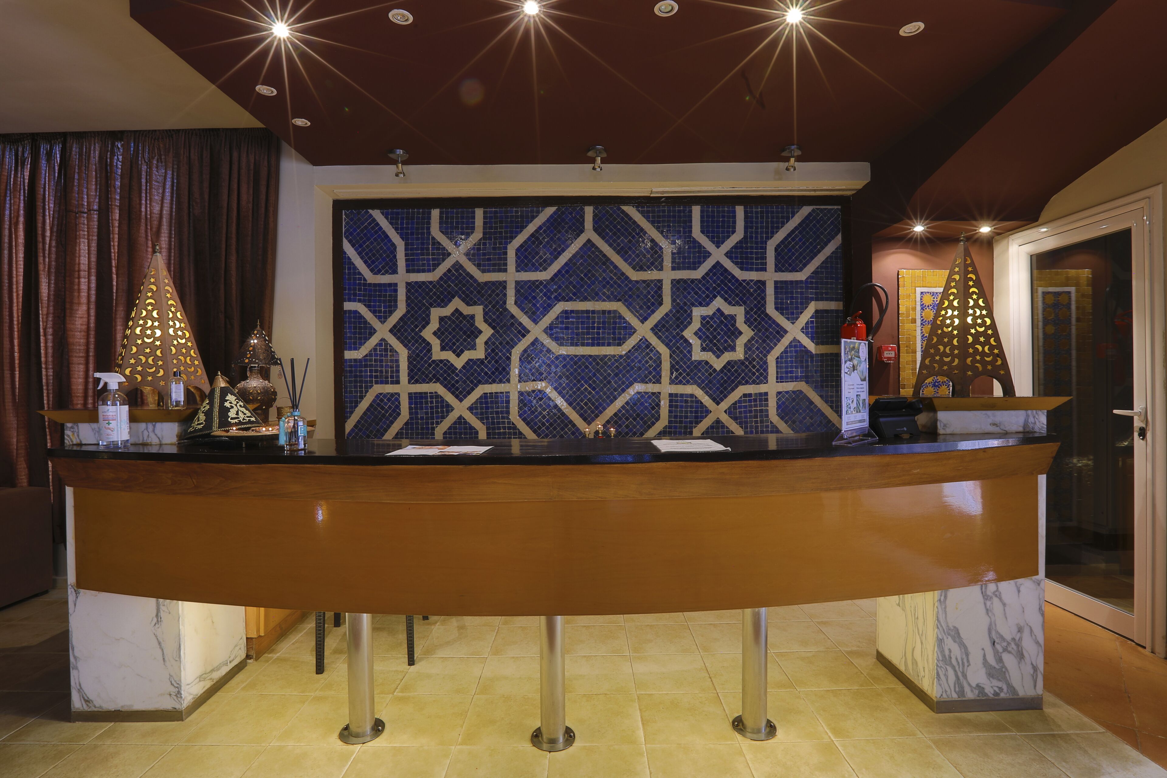Bancada de recepção com base de mármore, parede com padrão decorativo e design moderno no teto.