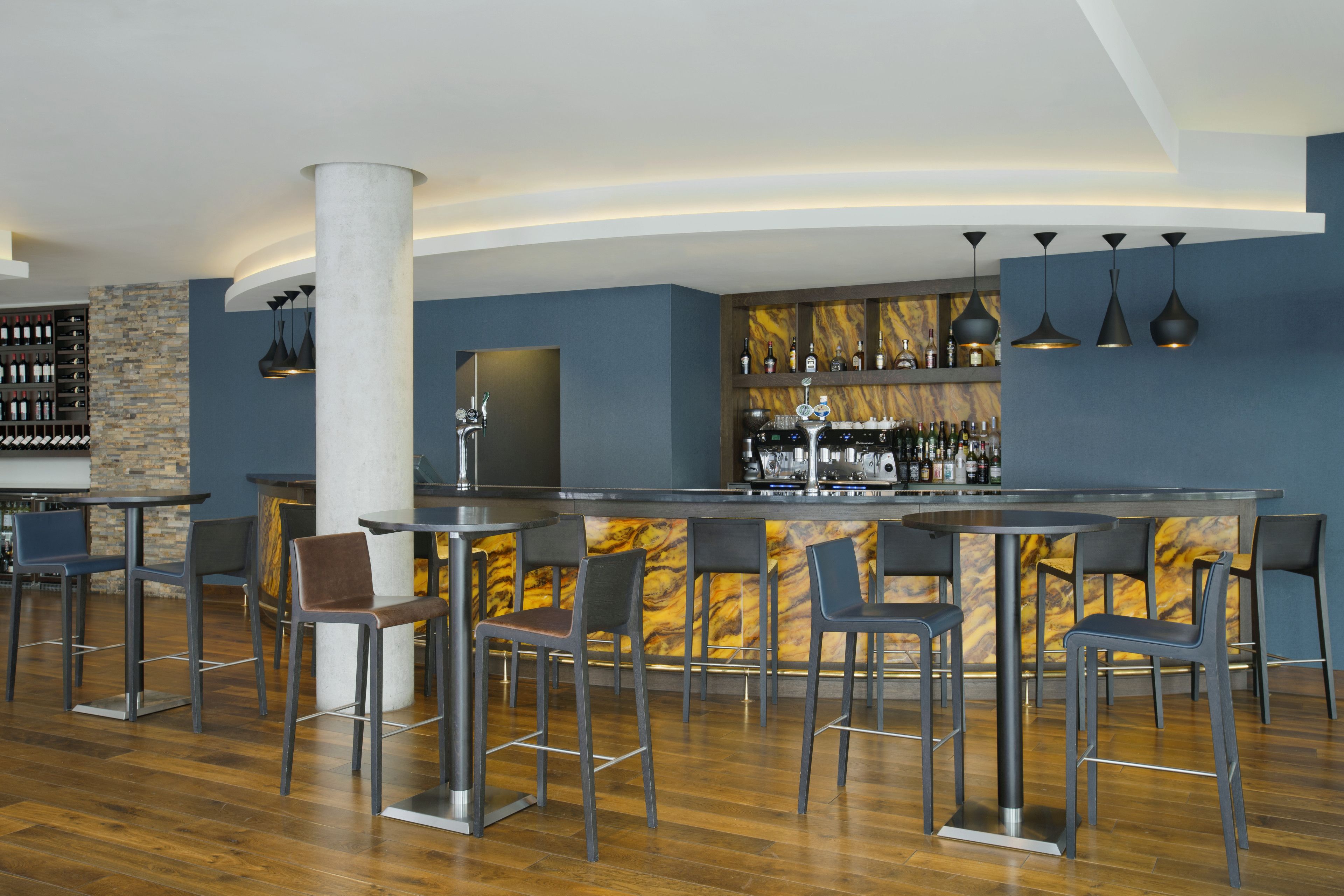 Uma área de bar moderna com bancada de mármore, banquetes e um espaço para vinhos.