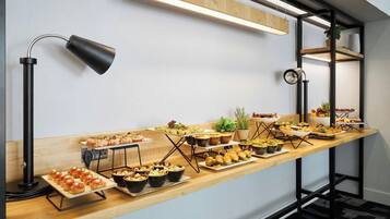Mesa de buffet com diversos alimentos e iluminação moderna.