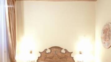 Quarto com uma cama grande, duas mesinhas de cabeceira, uma cadeira e um teto decorativo.