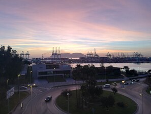 Uma área industrial costeira com várias guindastes e uma grande extensão de água.