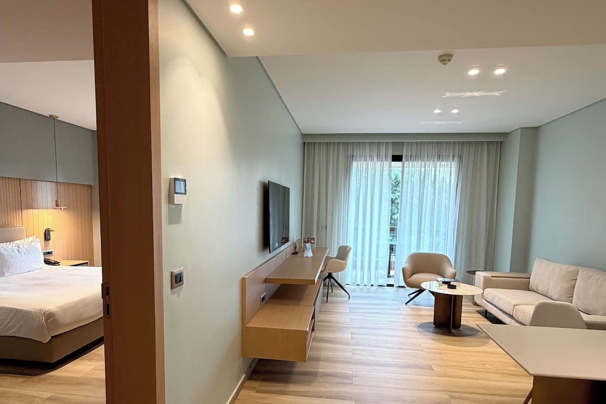 Quarto de hotel moderno com cama, escrivaninha, sofá e televisão.