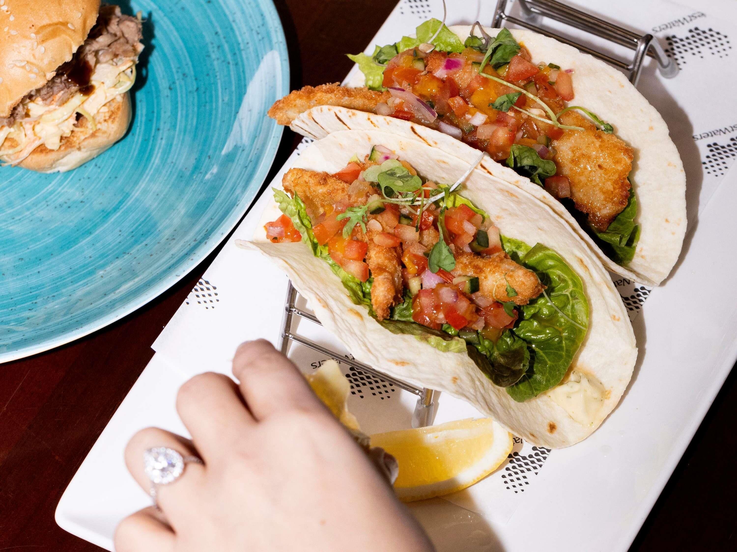 Um prato com dois tacos e um hambúrguer em um prato azul.