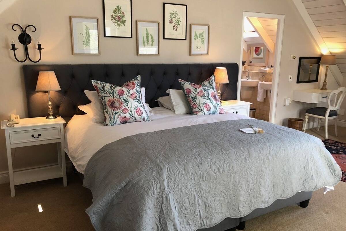 Quarto com cama grande, duas mesas de cabeceira, uma cabeceira e impressões botânicas emolduradas na parede.
