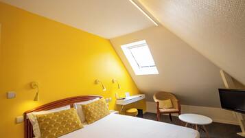 Quarto de hotel com uma cama, escrivaninha, cadeira e televisão.
