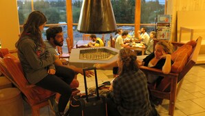 Um grupo de pessoas sentadas à volta de uma mesa numa sala com grandes janelas que oferecem vista para uma paisagem montanhosa.