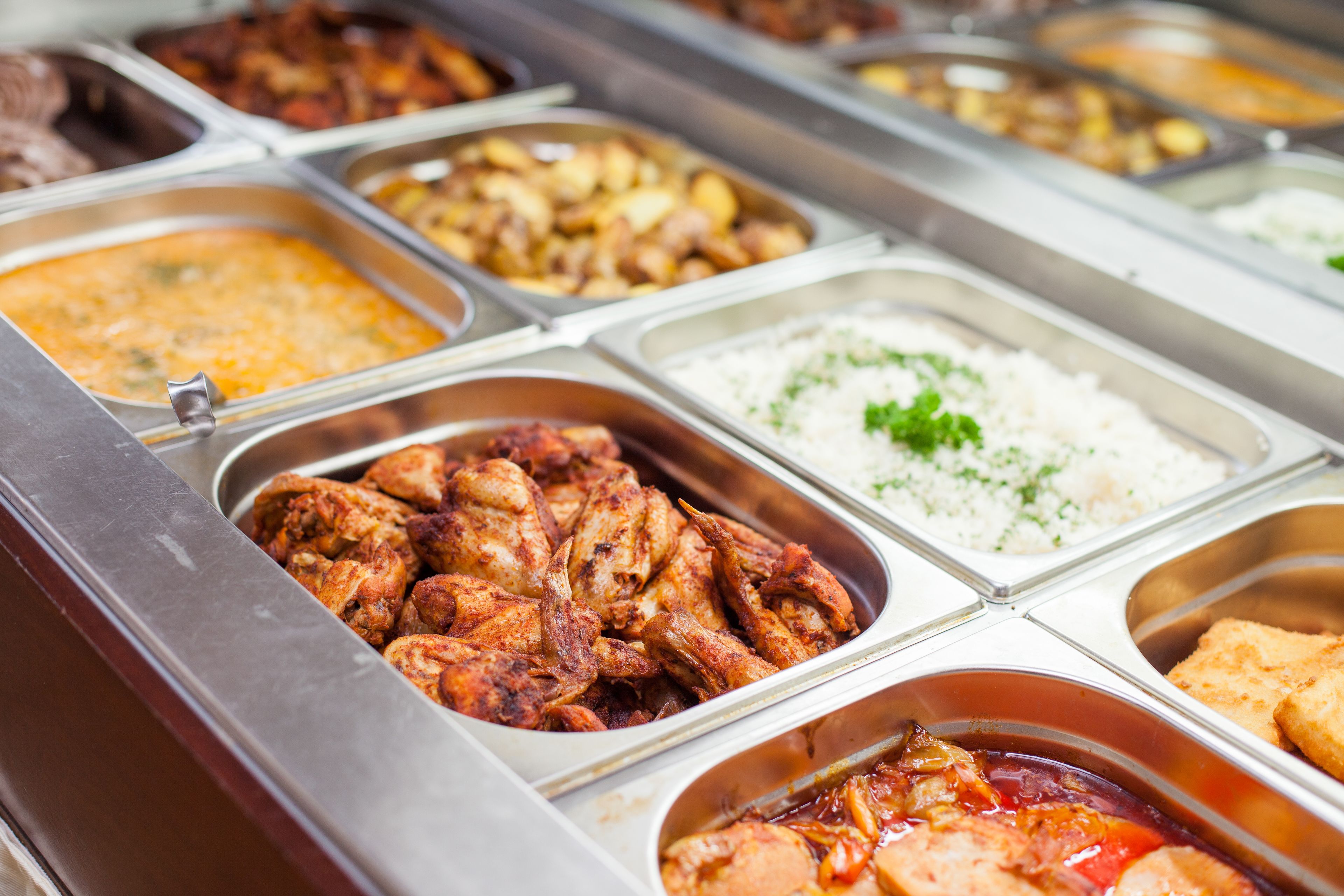 Buffet com diversas opções de comida, incluindo arroz, frango e outros pratos.