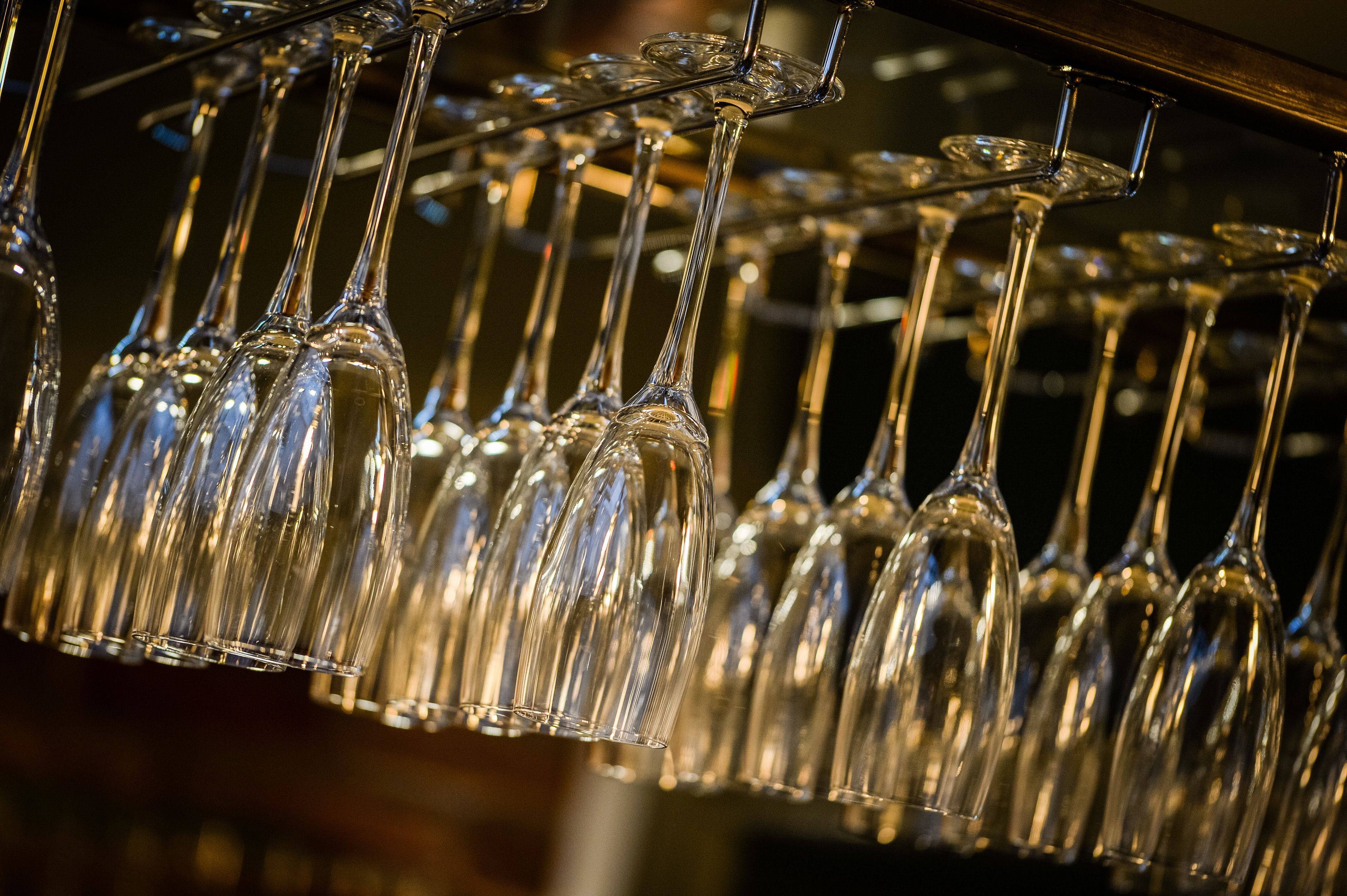 Vários copos de vinho vazios pendurados numa estrutura.