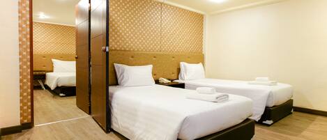 Quarto de hotel com duas camas, piso de madeira, parede estampada e um espelho.