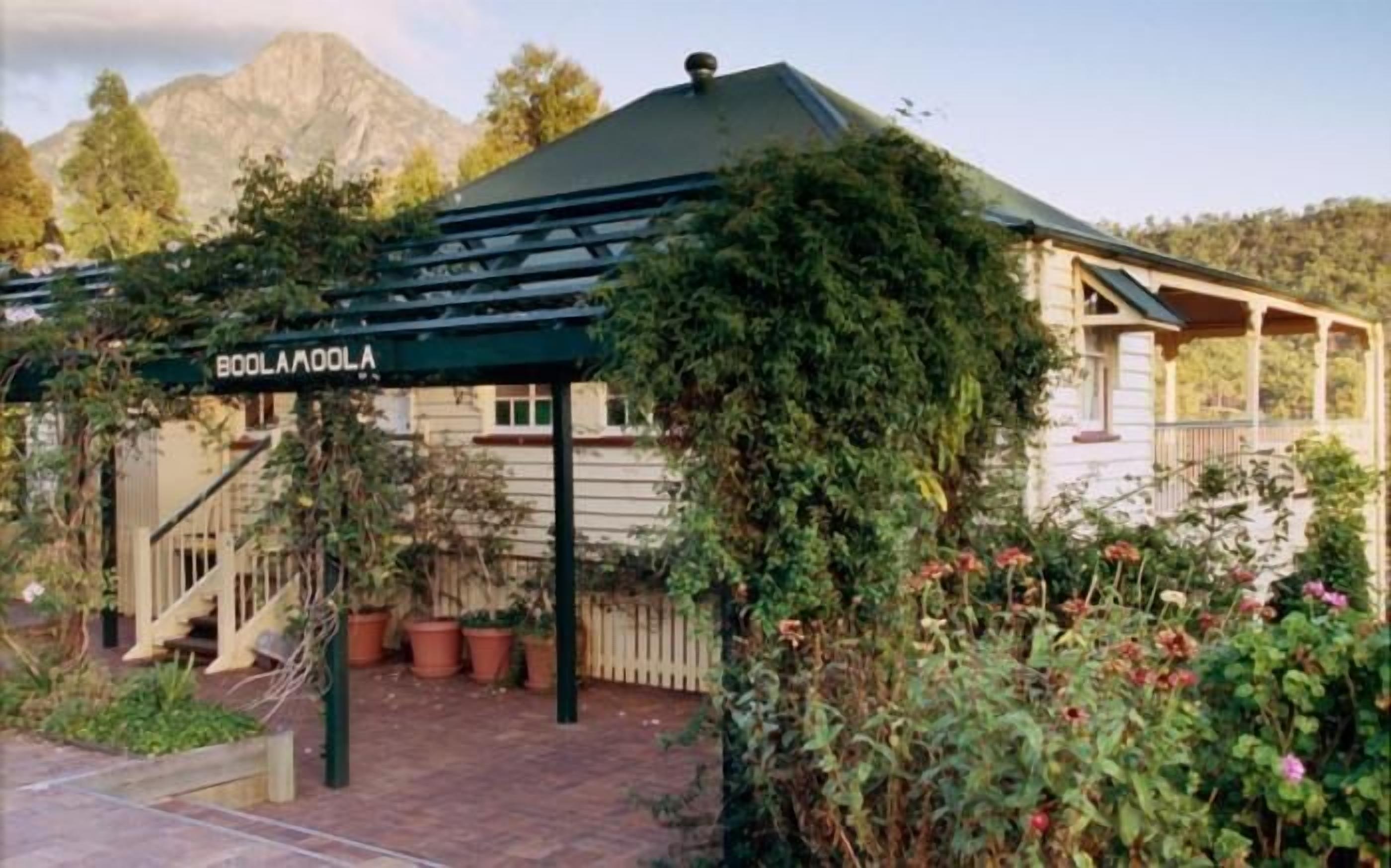 Um edifício com uma placa indicando "BOOLA AOLA" e uma escadaria coberta que leva à entrada.