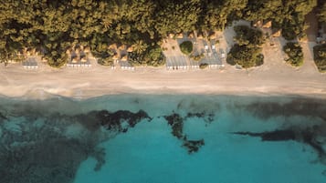 Na praia, praia de areia branca, guarda-sóis de praia, toalhas de praia