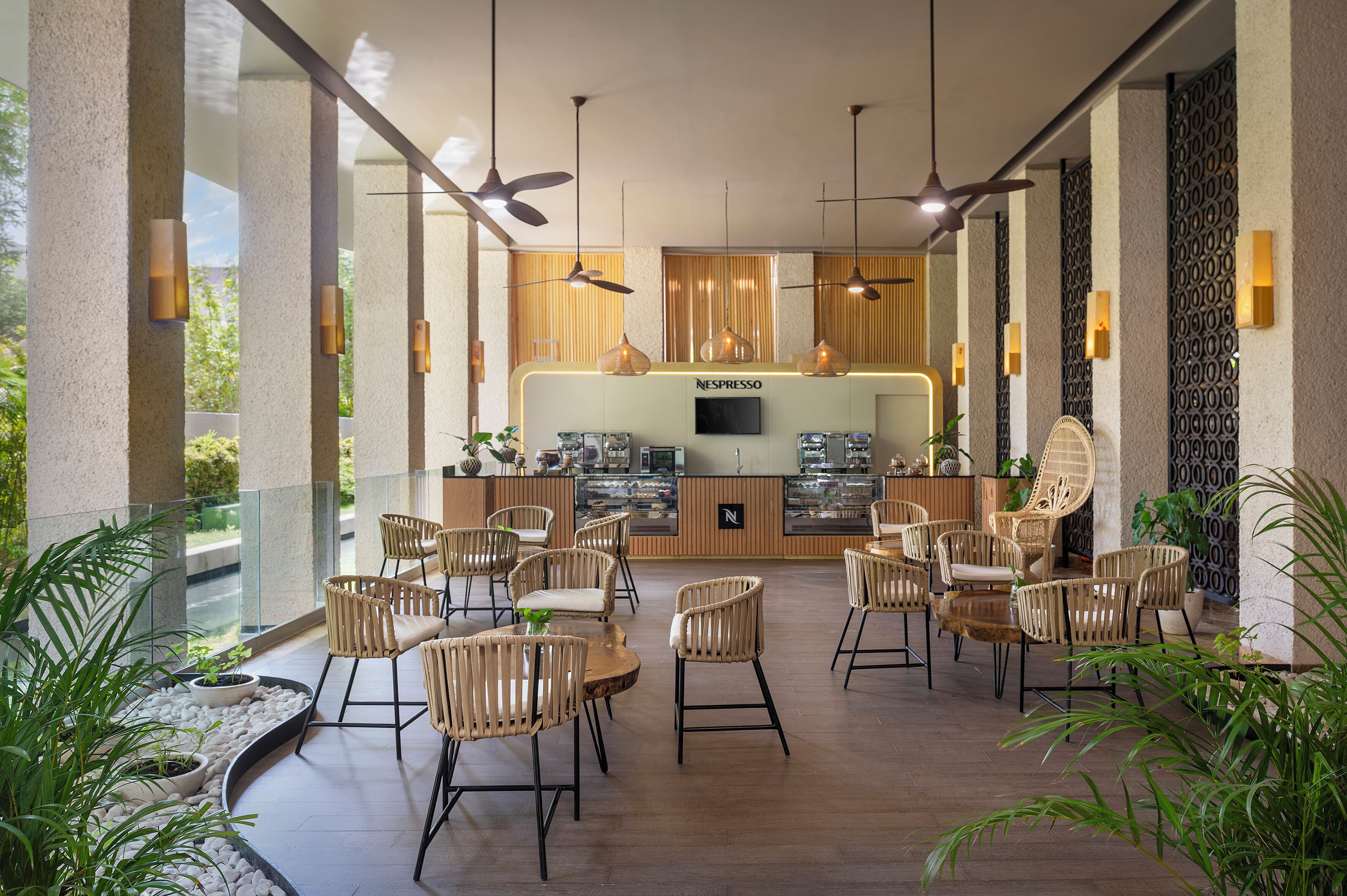 Um café moderno com cadeiras de vime, balcão de café e uma televisão de tela plana.