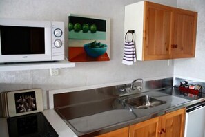 Cozinha com micro-ondas, pia, armários de madeira e um quadro de maçãs.