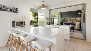 Cozinha moderna com ilha central, banquetas e vista para a área externa.