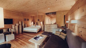 Interior de uma cabana de madeira com cama, sofá e área de jantar.