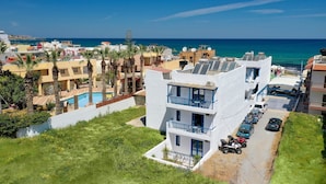 Zona residencial costeira com um edifício branco com varandas, piscina e vista para o mar.