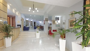Um hall amplo com balcão de recepção, área de estar e escadaria para os andares superiores.