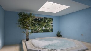 Um quarto de spa com hidromassagem, uma claraboia e um grande mural na parede.