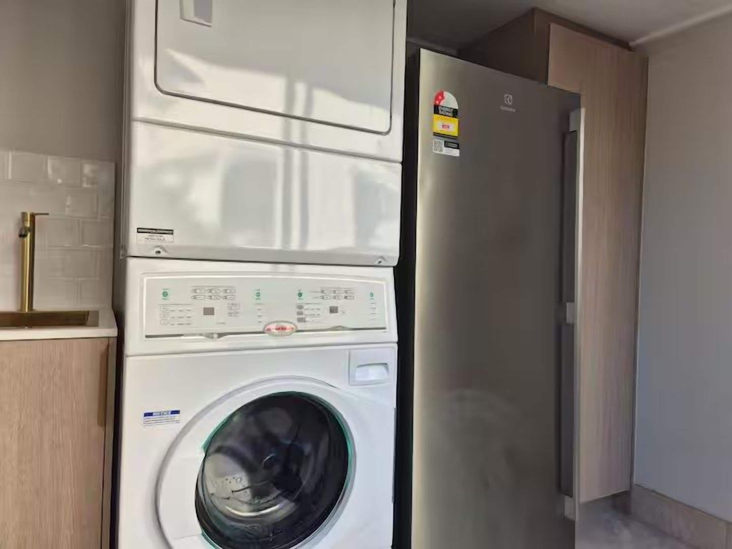 Uma área de lavanderia compacta, com máquina de lavar e frigorífico.