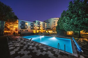 Um hotel com piscina, área de estar externa e fachada bem iluminada.