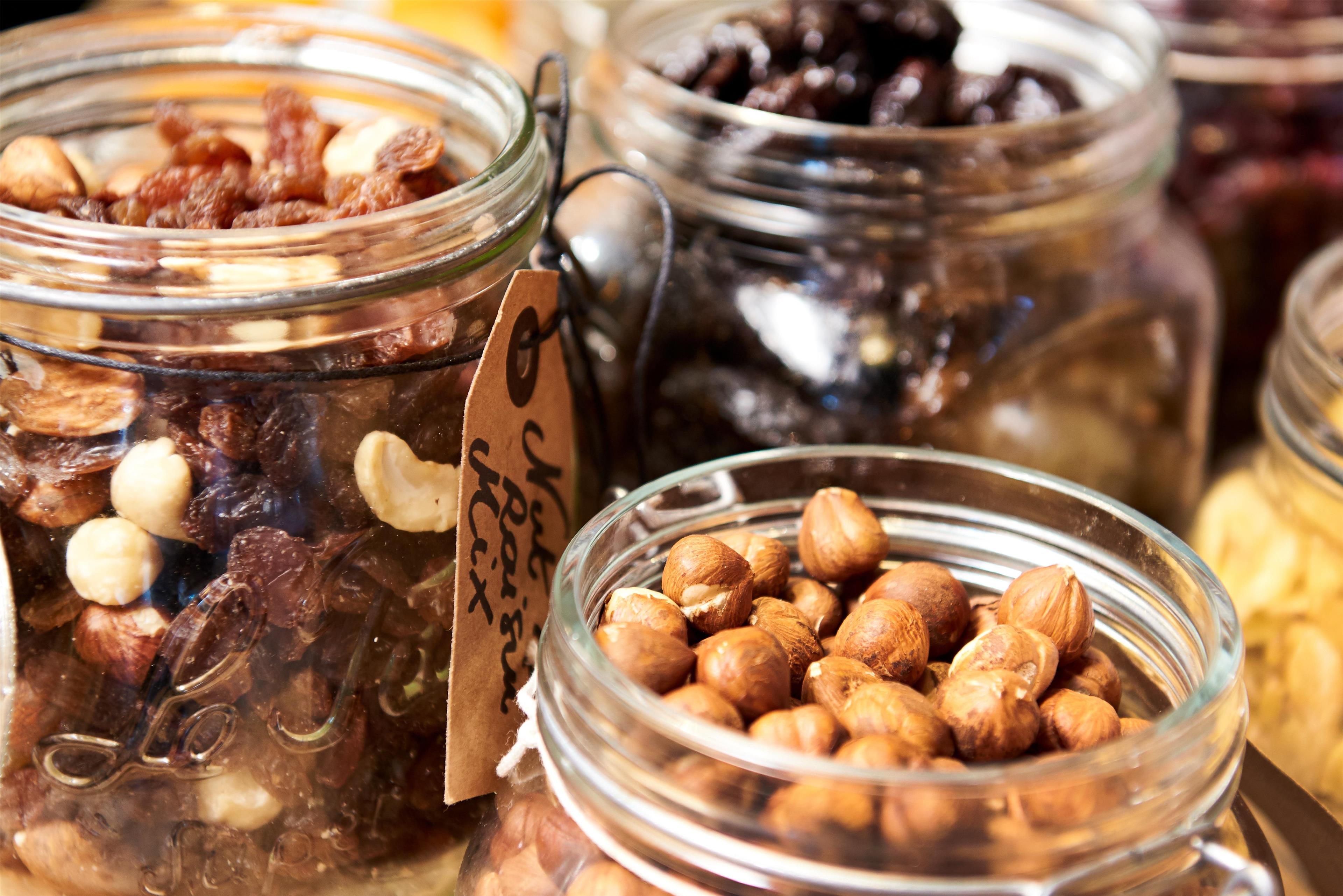Diversos alimentos em frascos de vidro, incluindo nozes e frutas secas.
